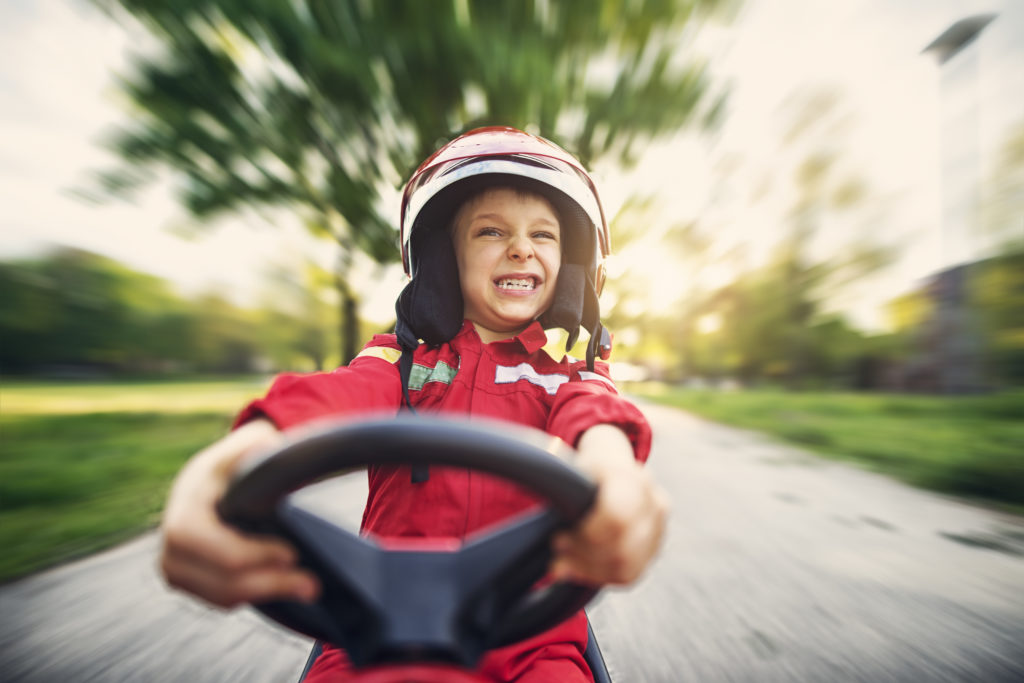 Little boy driving fast a go kart. The cute boy is aged 6 and is making ...